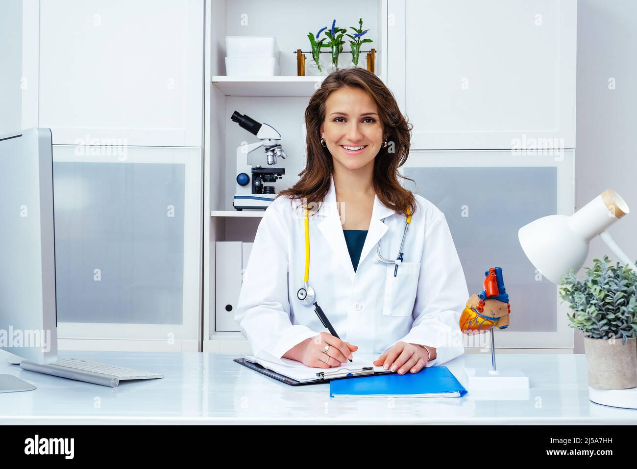 beautiful smiling female doctor showing human heart mockup in office ...