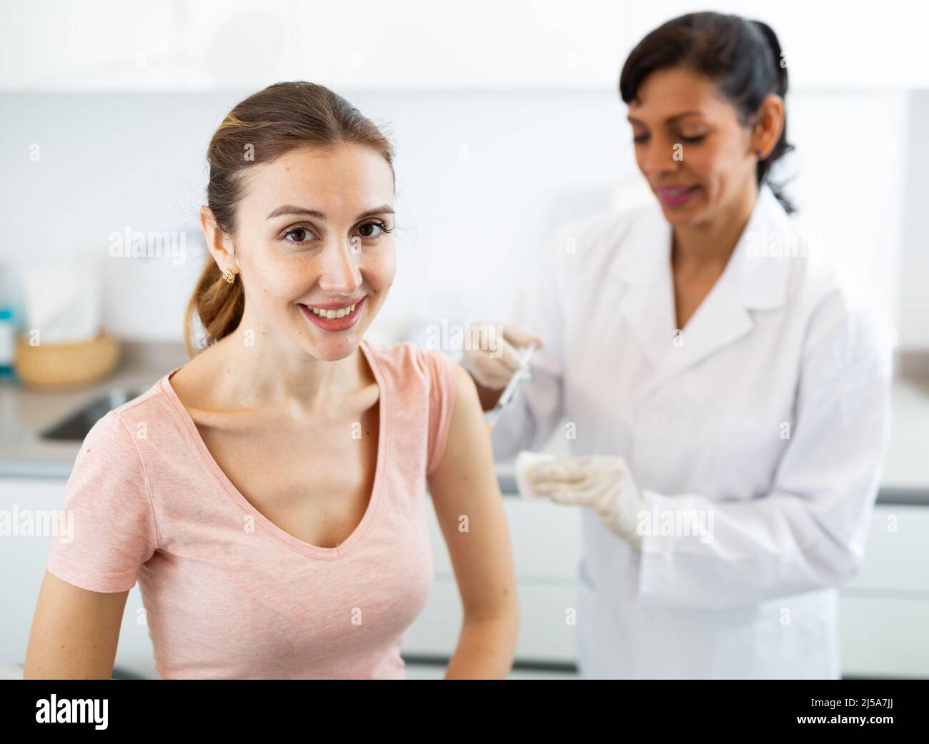 Young woman getting injection at doctors office Stock Photo - Alamy