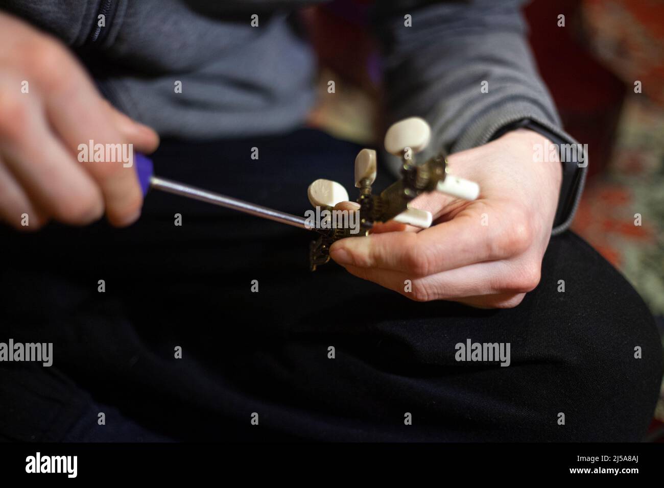 The musician tunes the guitar. Acoustic instrument. Do-it-yourself ...