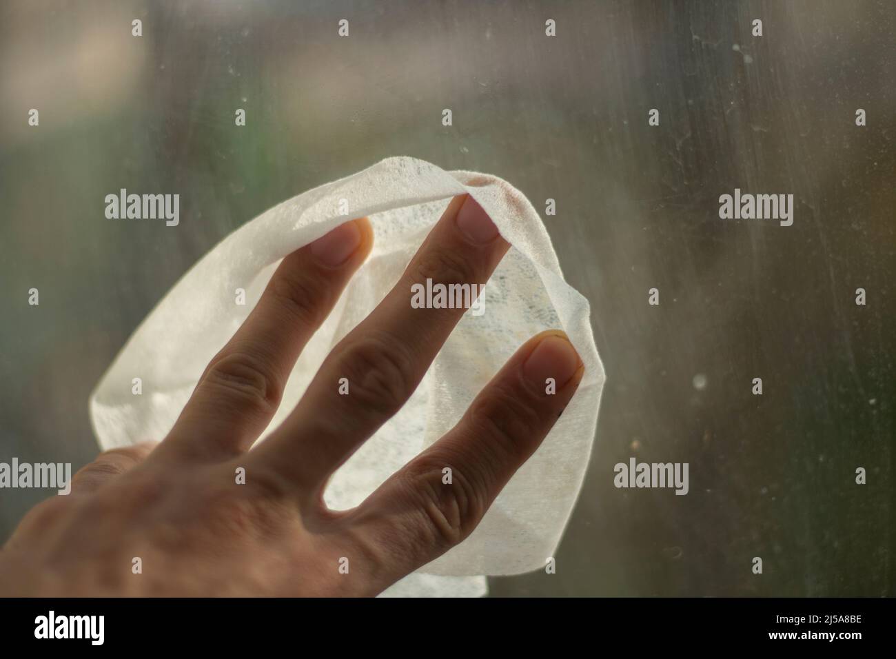 Wiping window from dirt. Cleaning of room. Erasing dust with damp cloth ...