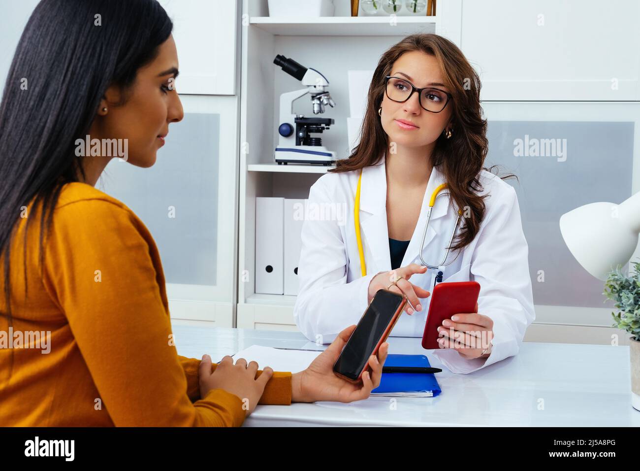 female doctor with patient using mobile phones in hospital healthcare ...