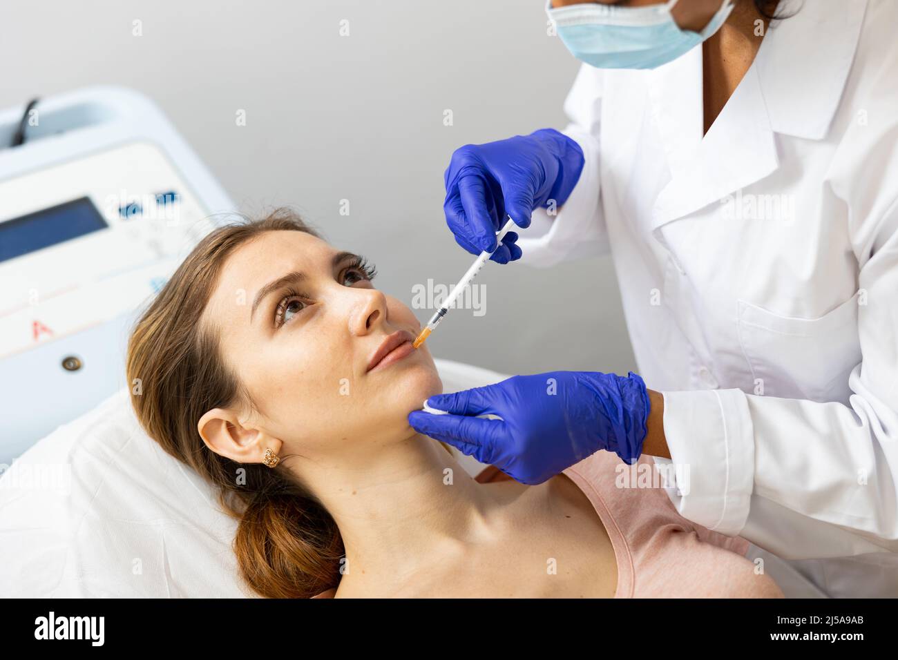 Woman cosmetician giving lip injections of botulinum toxin for young ...