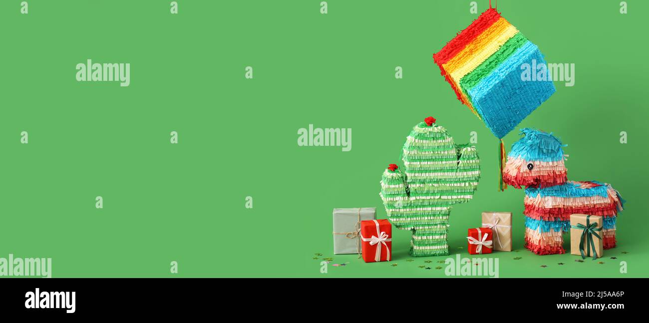 Mexican pinatas with gifts on green background with space for text ...