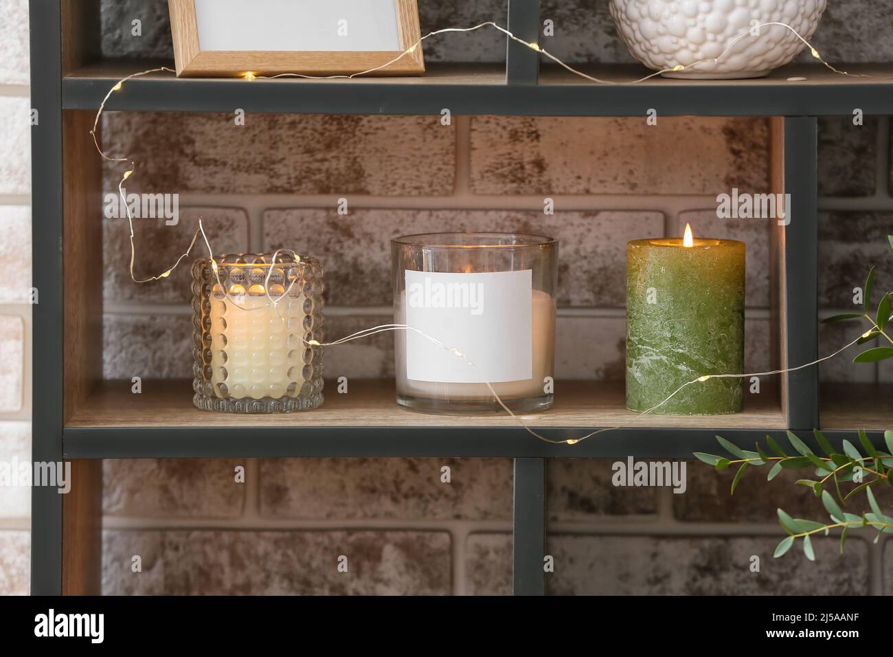 Holders with burning candles on shelf unit Stock Photo - Alamy