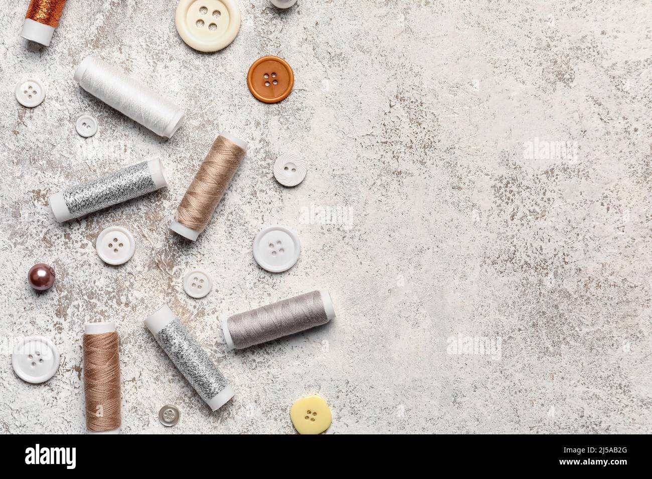 Sewing threads with buttons on light background Stock Photo - Alamy