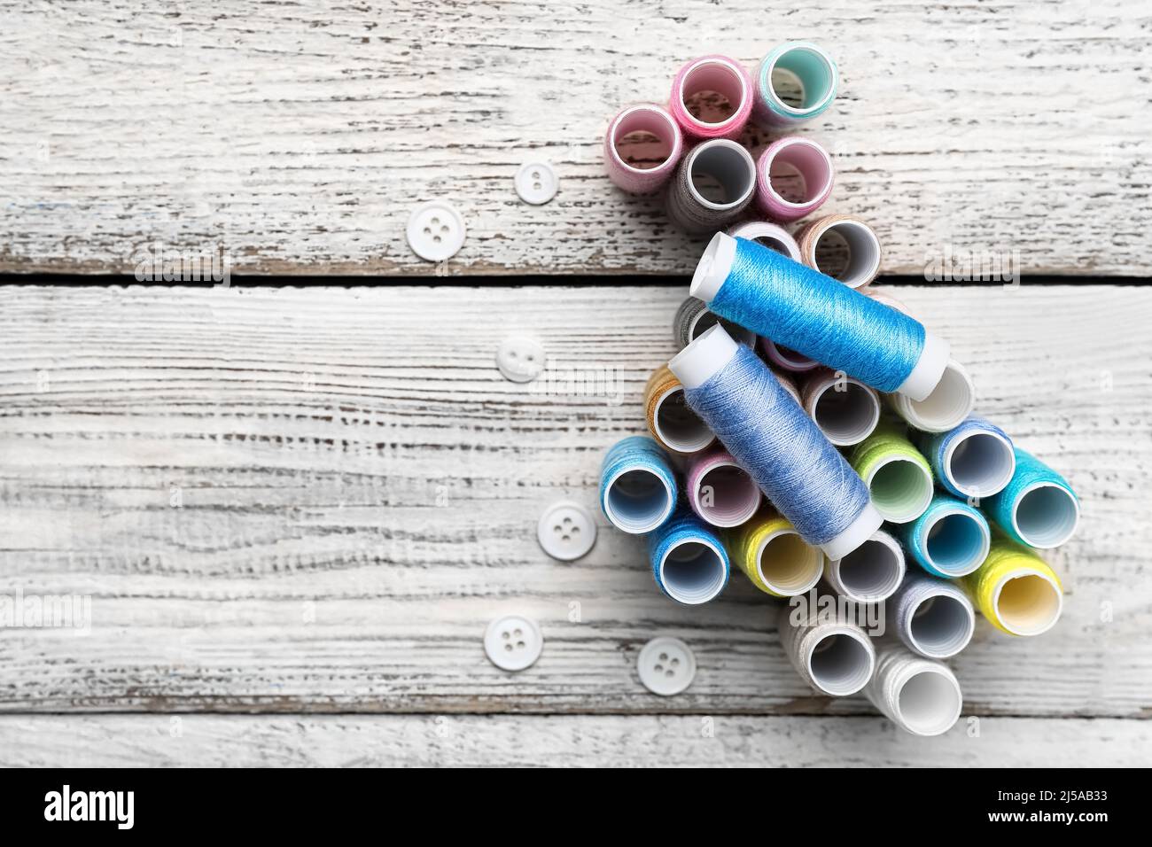 Sewing threads and buttons on light wooden background Stock Photo - Alamy