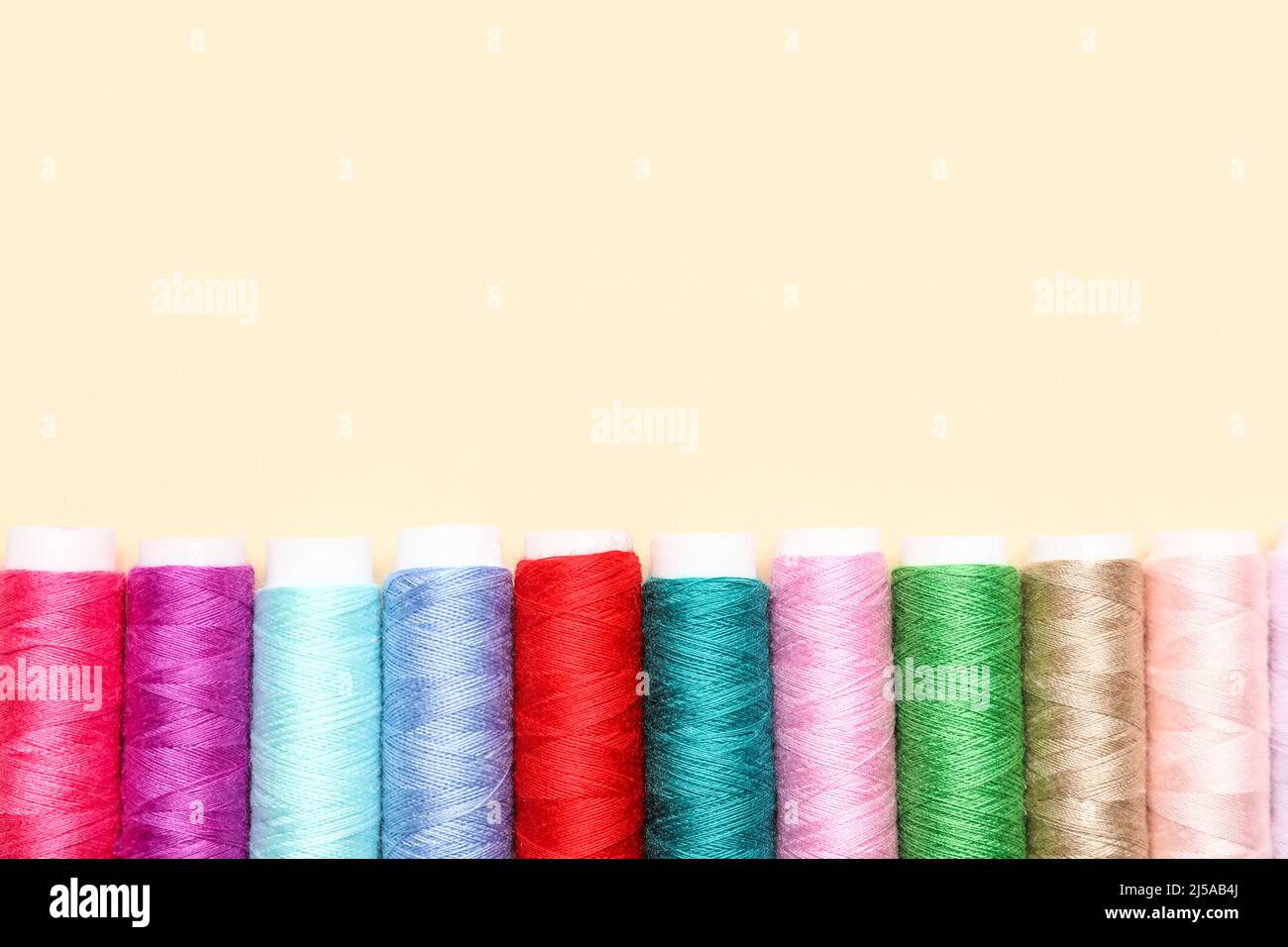 Sewing threads on beige background Stock Photo - Alamy
