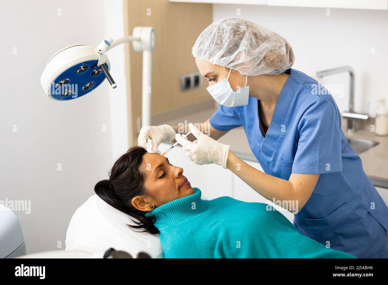 Female cosmetologist giving injections of botulotoxin for her patient ...