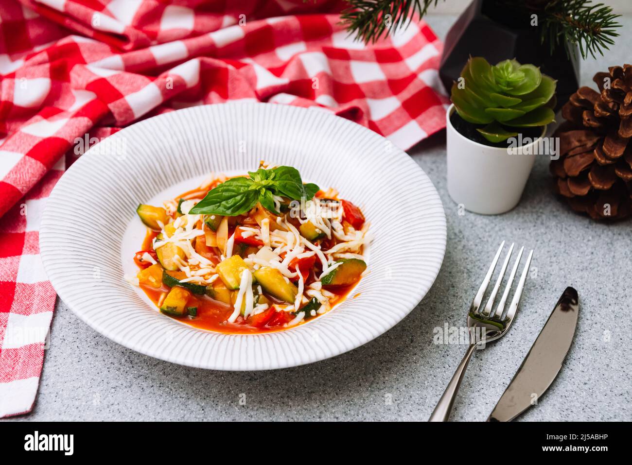 A deep plate of zucchini vegetable stew, with grated cheese and basil ...