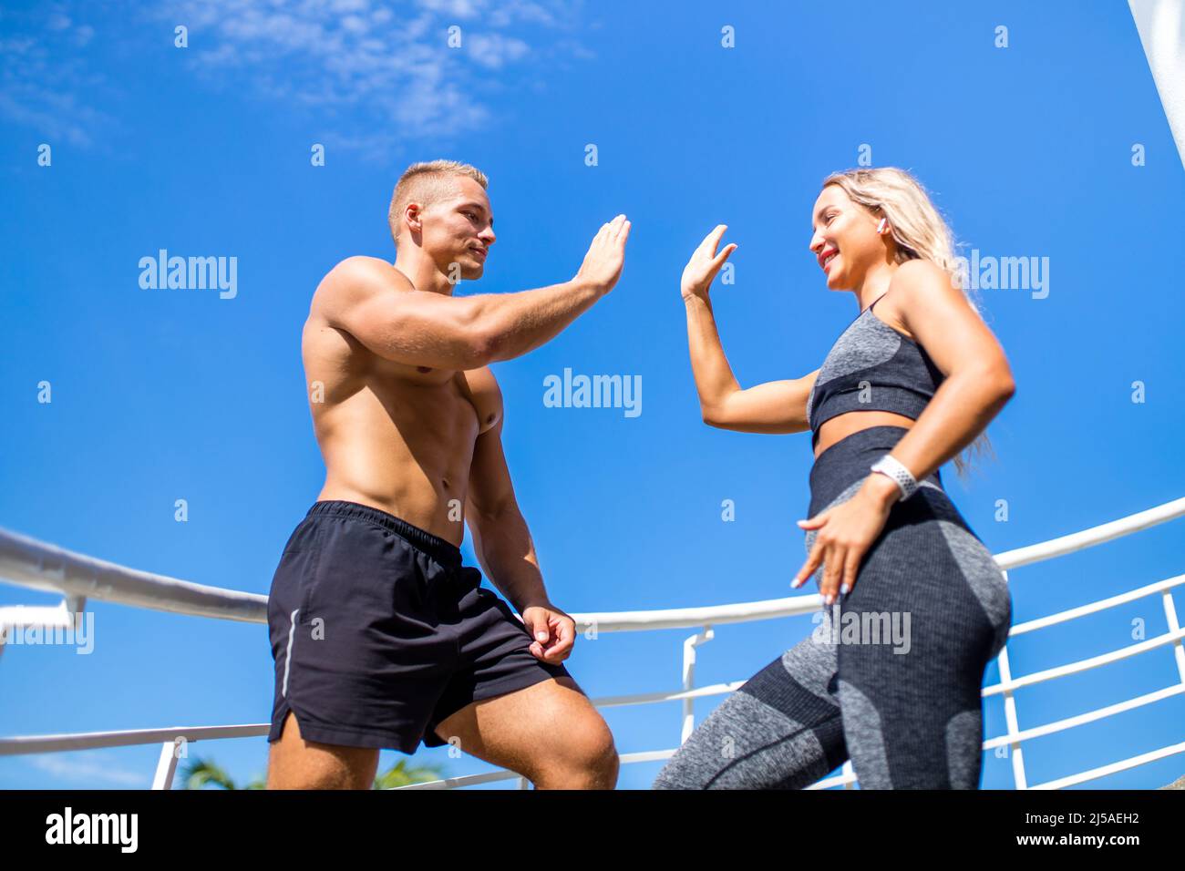 young couple in sport clothing doing stretching exercises together ...
