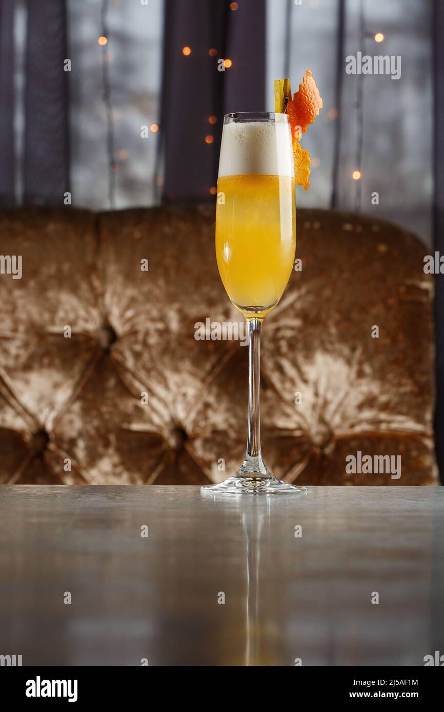 Glass of a delicious yellow cocktail French 75 standing on the bar ...