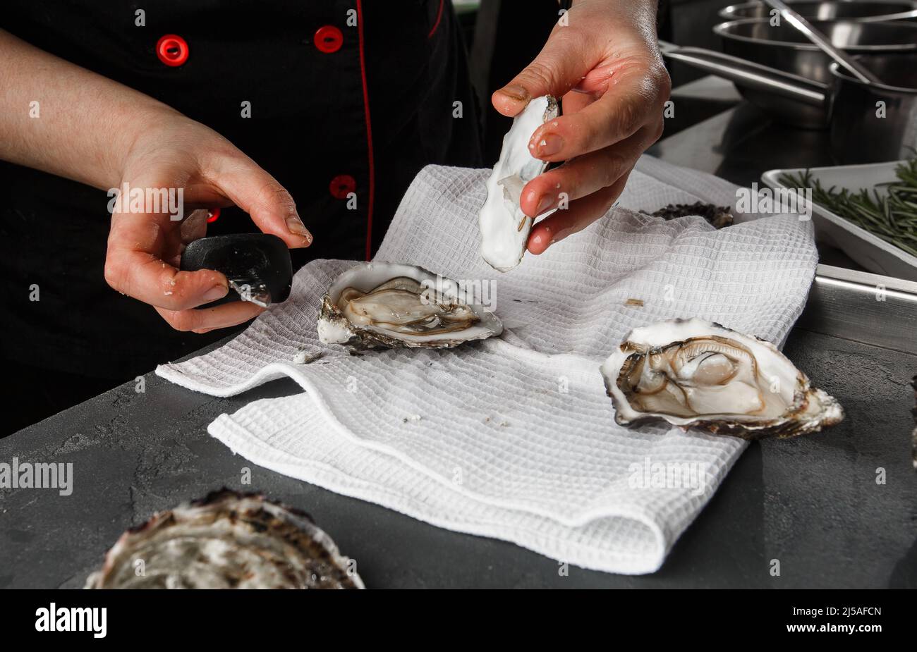 Someone shucking an oyster as water drips out of it. The oyster opening ...