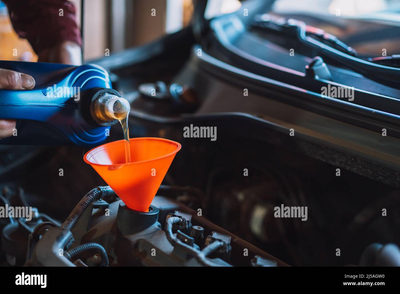 The mechanic pours new oil into the engine using funnel Stock Photo - Alamy