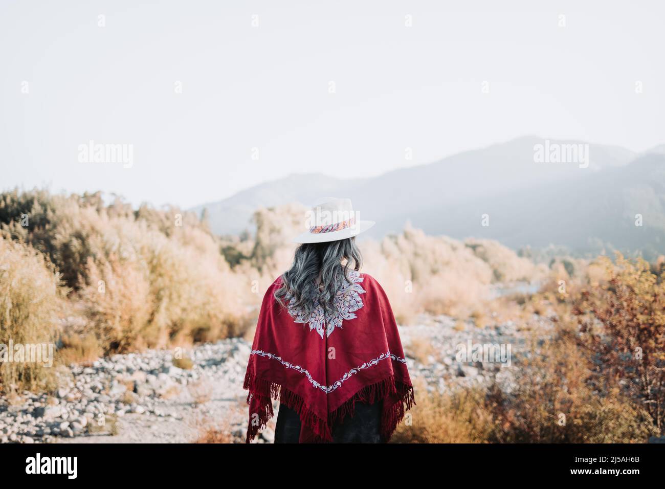 Traditional latin american woman wearing a red poncho and a hat seen ...