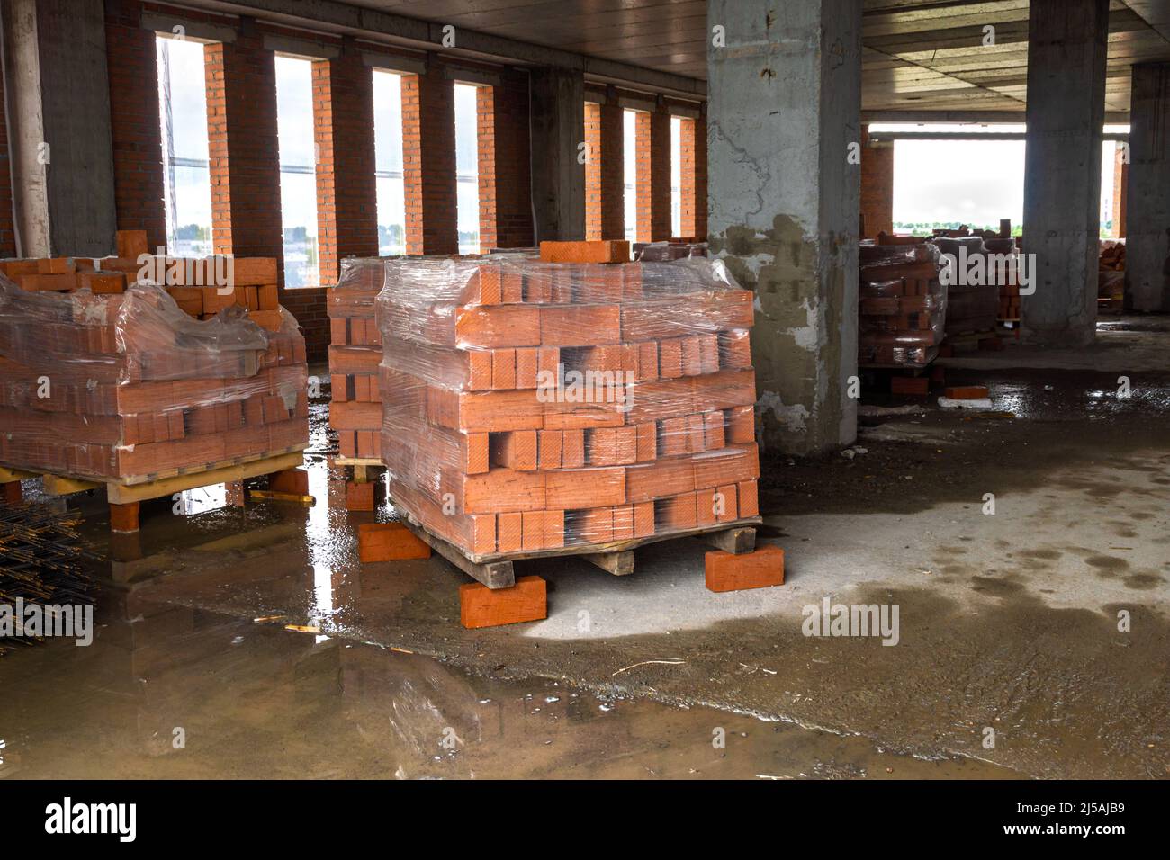 Pallets of bricks stand inside a monolithic frame building under ...
