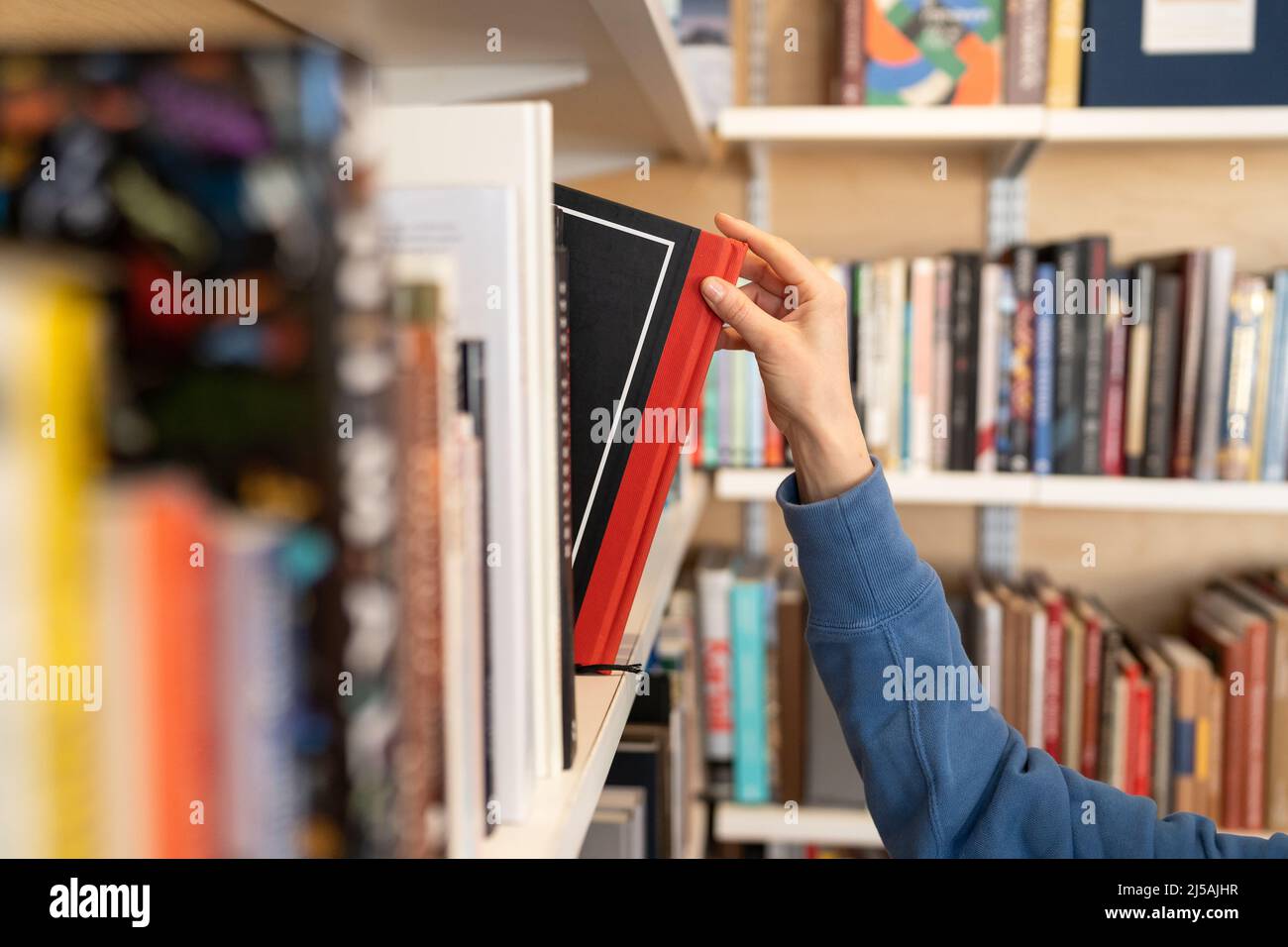 Woman hand picking book from bookshelf in library in university ...