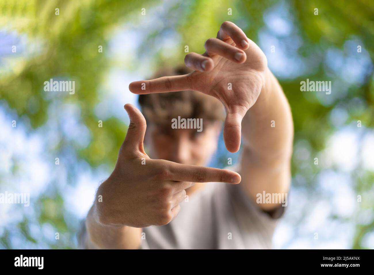 A handsome young man blinks his eyes and looks through a frame made up ...