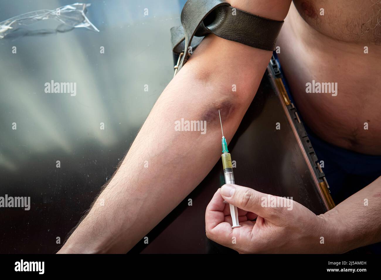 Addict injecting heroin dose to his hand with syringe. Man drugs ...