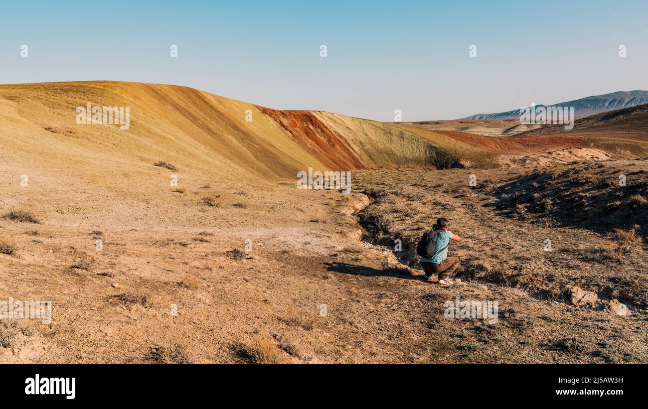 Photographer takes pictures of a beautiful red sandy mountain Stock ...