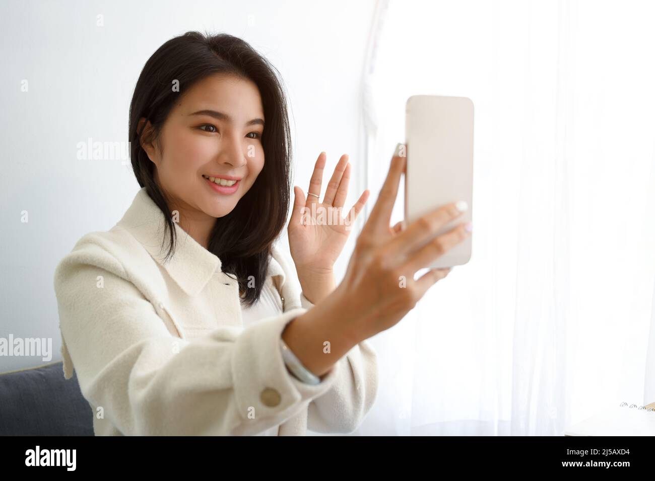 Beautiful and elegant Asian millennial woman sitting in a bright room ...