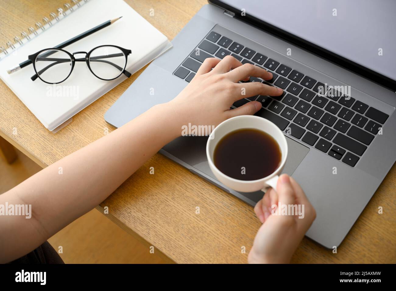Close-up, Female worker working on laptop computer while sipping hot ...