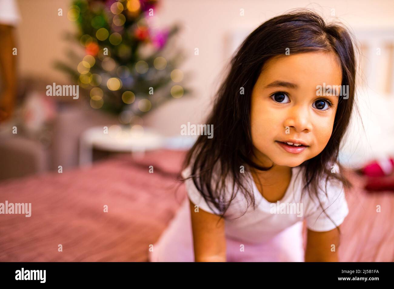 mixed race little cute girl awake in the xmas morning in bedroom and ...
