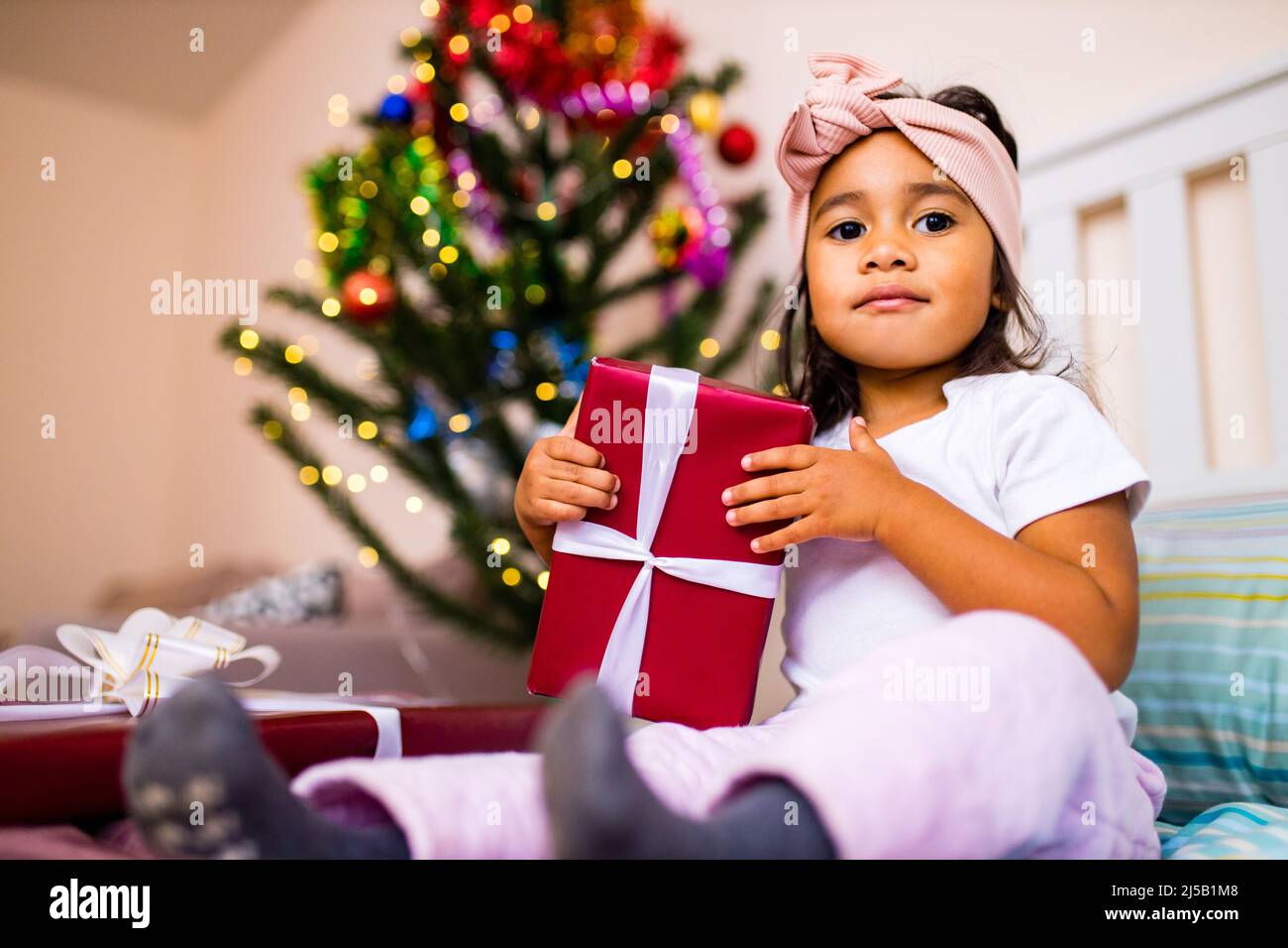 mixed race little cute girl awake in the xmas morning in bedroom and ...