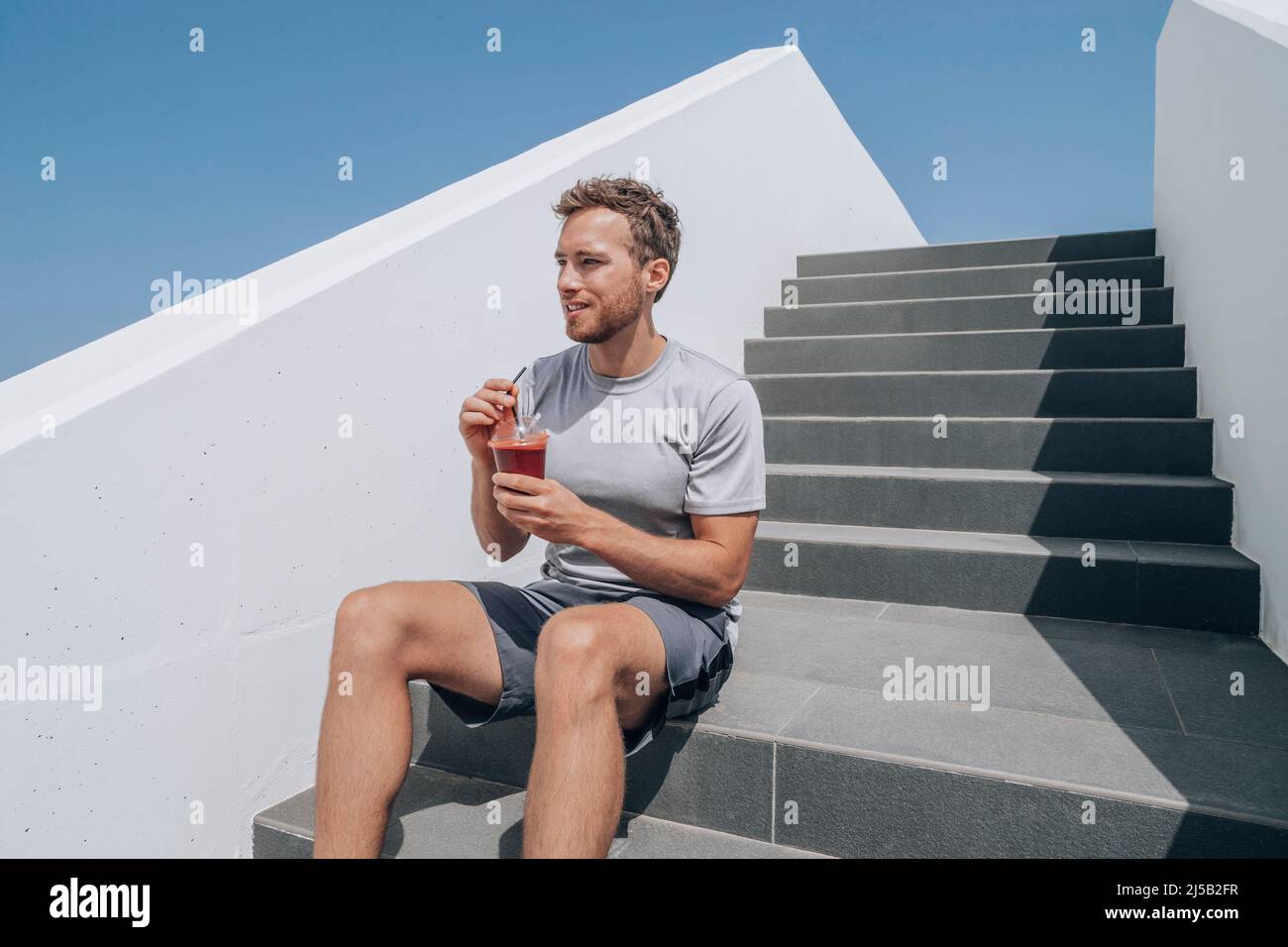 Man drinking healthy smoothie detox juice post cardio workout at gym ...