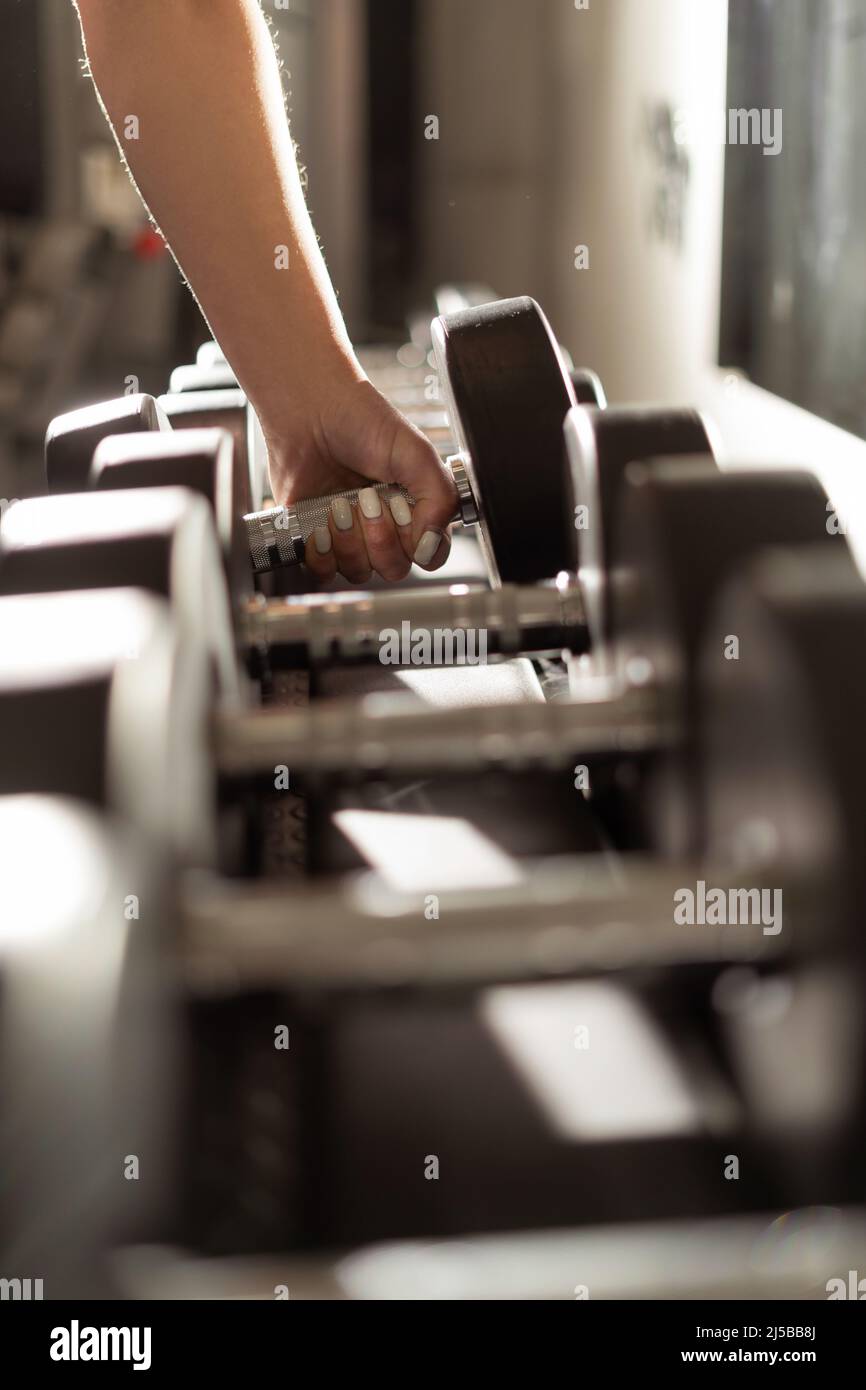 close-up of a female hand takes a dumbbell in the gym. sport and ...