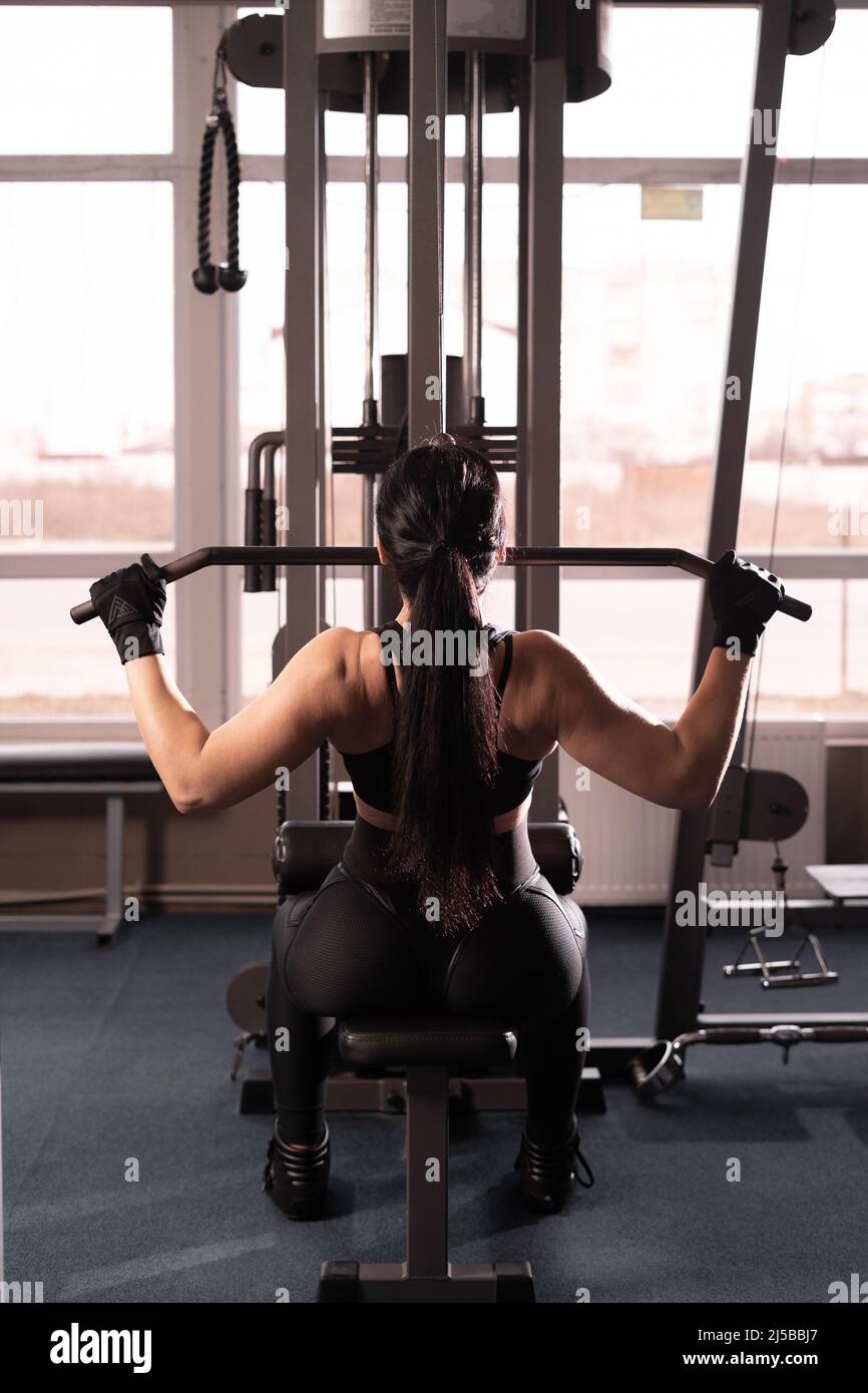 Shoulder lowering machine. Fitness woman is training in the gym. Upper ...