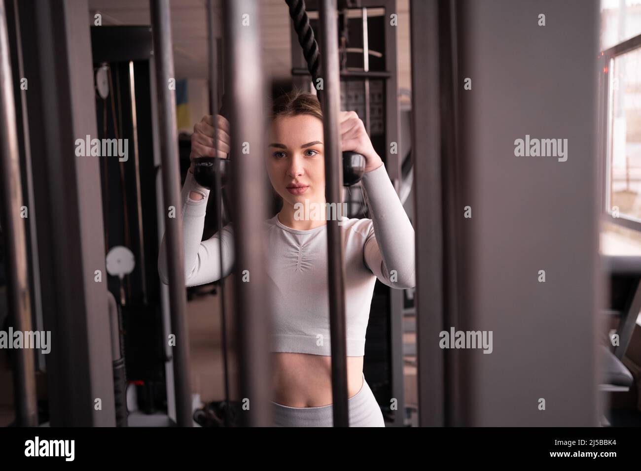 Young woman trains with weights in the gym. Exercises on the simulator ...