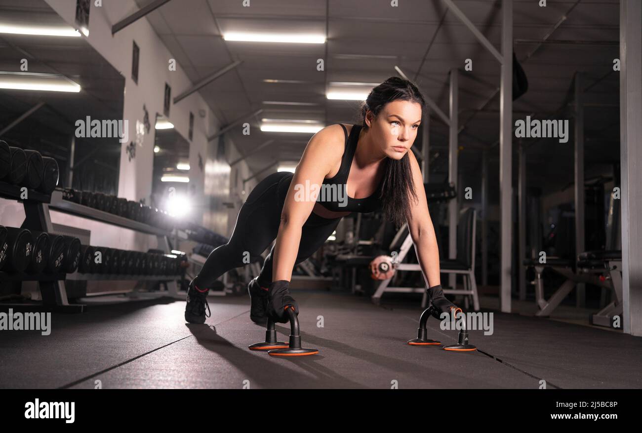 A beautiful athletic girl, dressed in a black sports top and tights ...