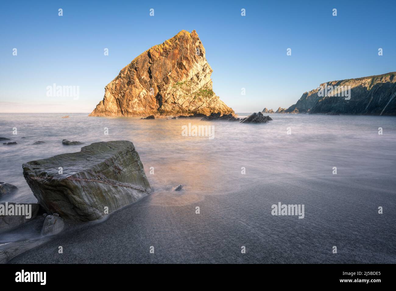 Curious rock with a diagonal vein of quartz on a beach in Loiba ...