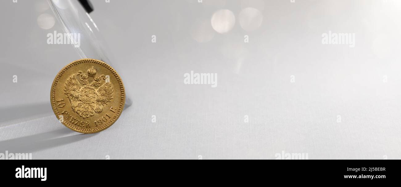 Numismatics. Gold coin 10 rubles 1901 and a magnifying glass. Light ...