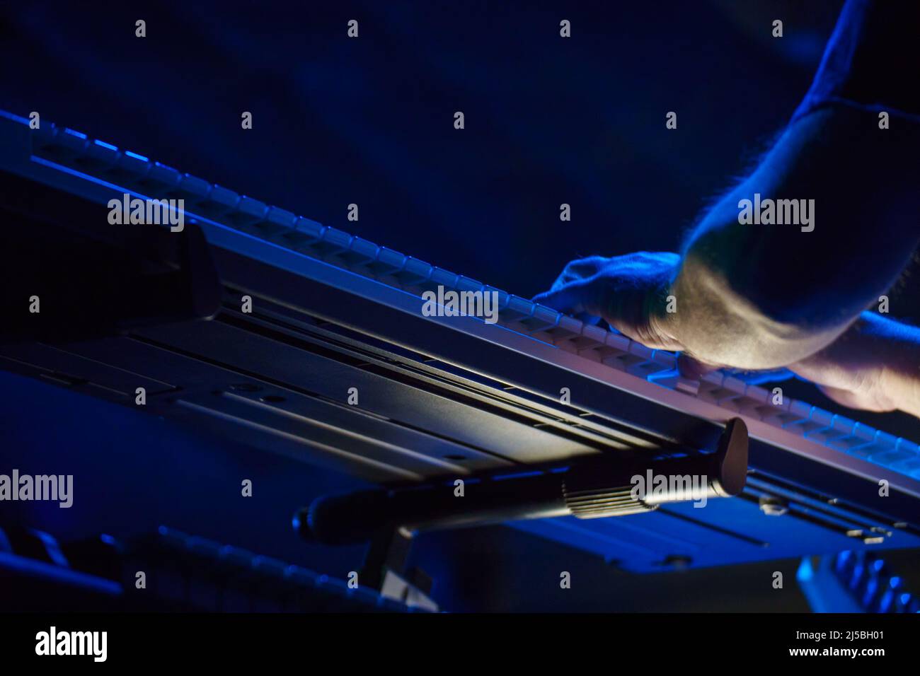 A pianist or keyboardist plays on stage a synthesizer in the spotlight ...