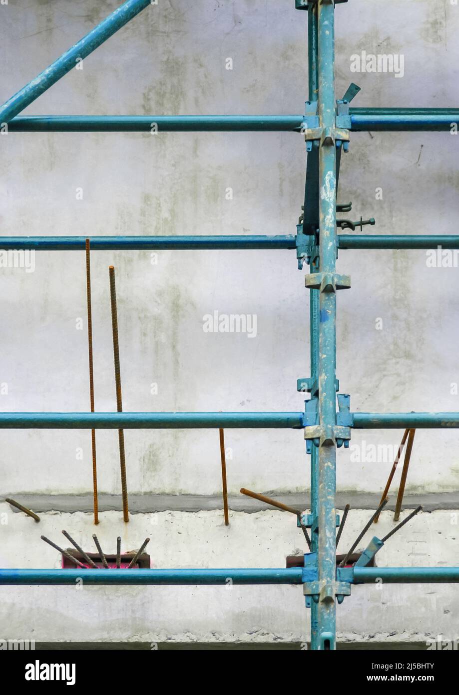 A concrete structure with blue scaffolding and exposed rebar, used for ...
