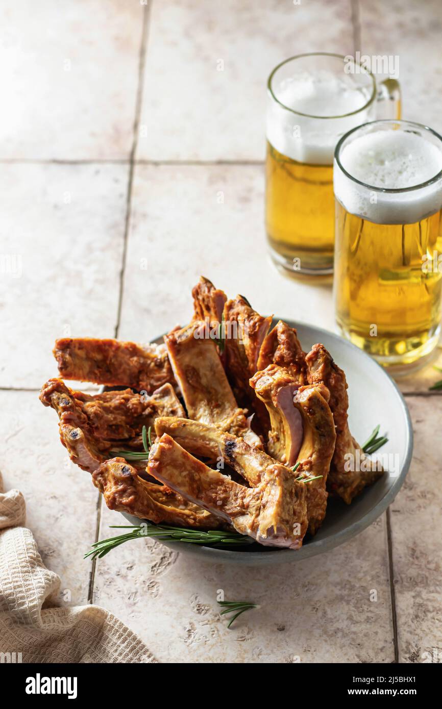 Smoked pork ribs with rosemary, beer and napkin on pink tile background ...