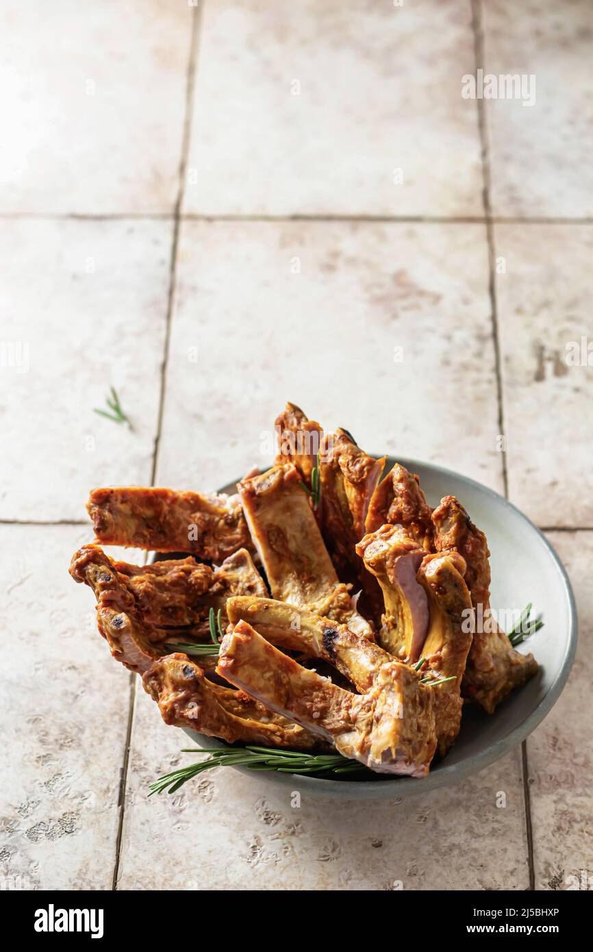 Smoked pork ribs with rosemary on pink tile background . Copy space ...