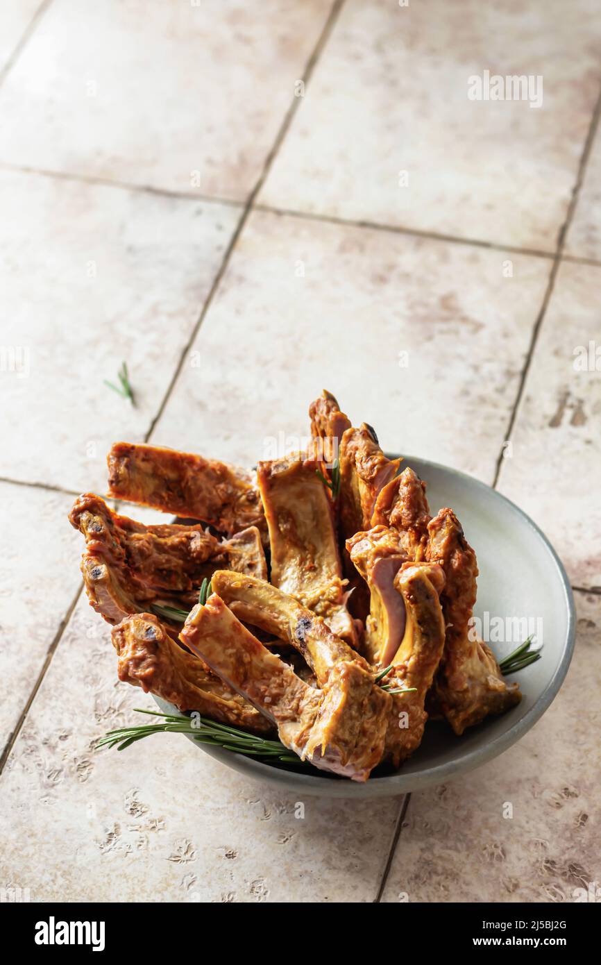 Smoked pork ribs with rosemary on pink tile background . Copy space ...