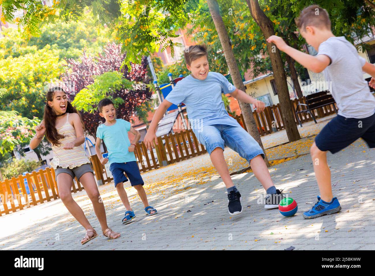Happy children playfully running after ball outdoors in park Stock ...