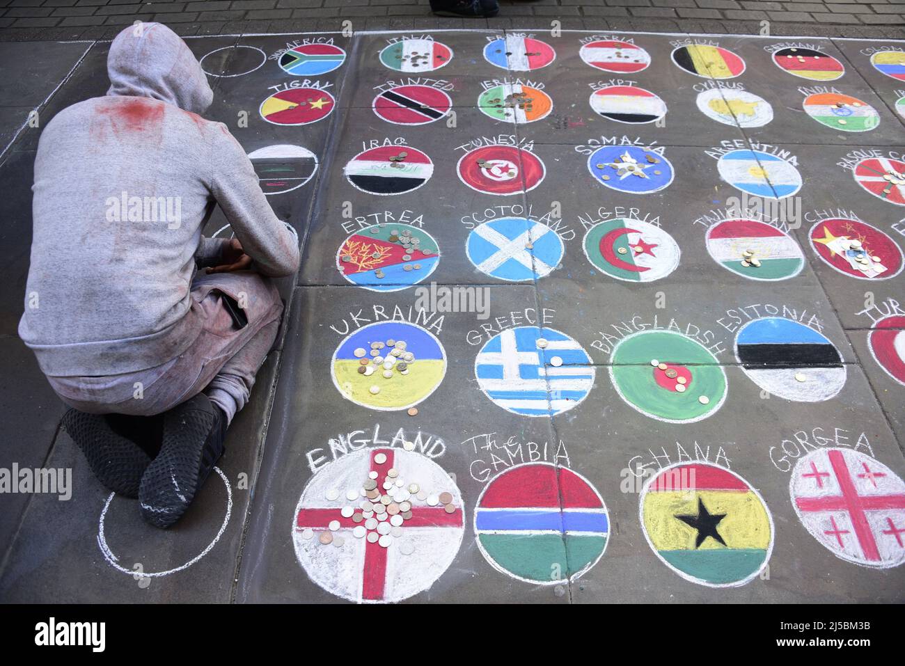 A pavement artist, wearing a grey tracksuit, draws images of many ...