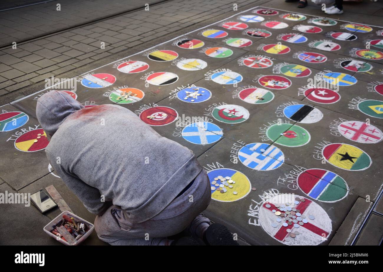 A pavement artist, wearing a grey tracksuit, draws images of many ...