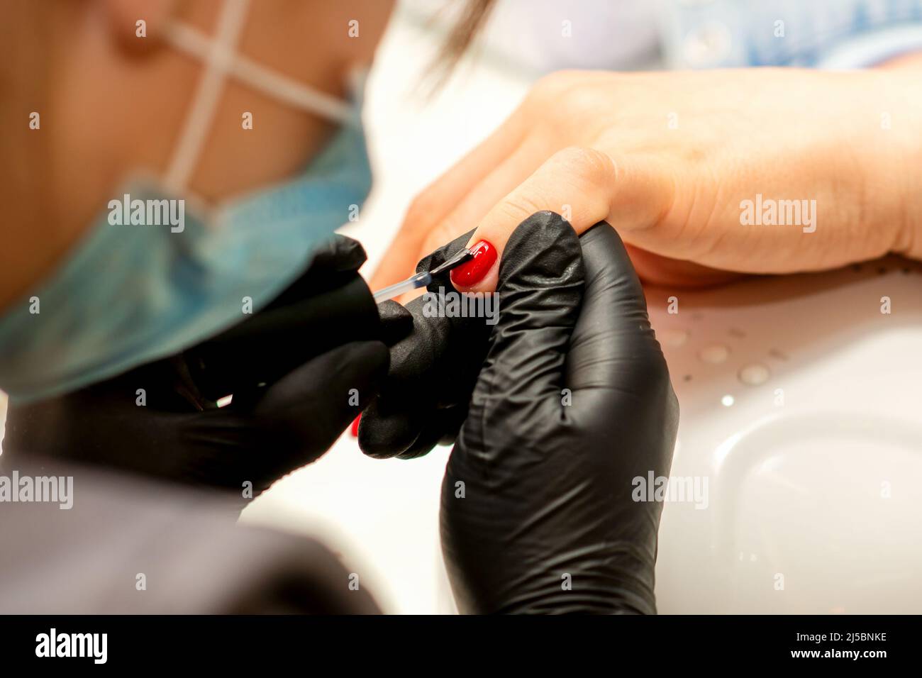 Professional manicure. A manicurist is painting the female nails of a ...