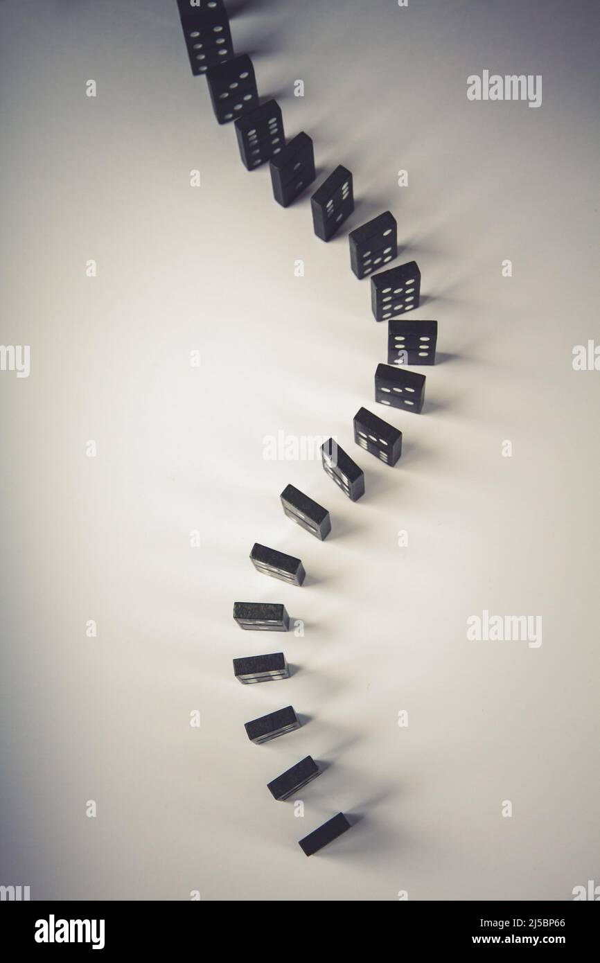 Black dominoes chain on a white table background. Domino effect concept ...