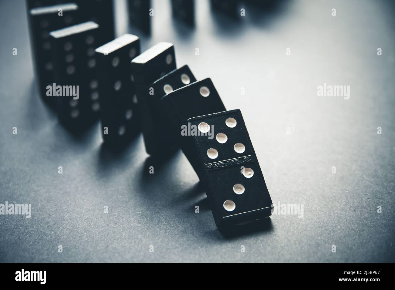 Black dominoes chain on a table background. Domino effect concept Stock ...