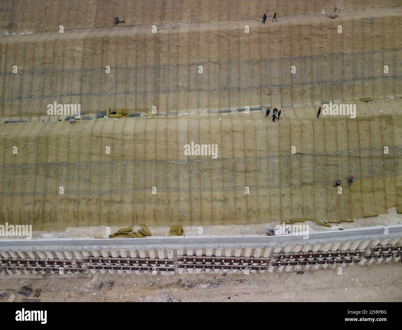Workers reinforce the slope over the new road. Road construction in ...