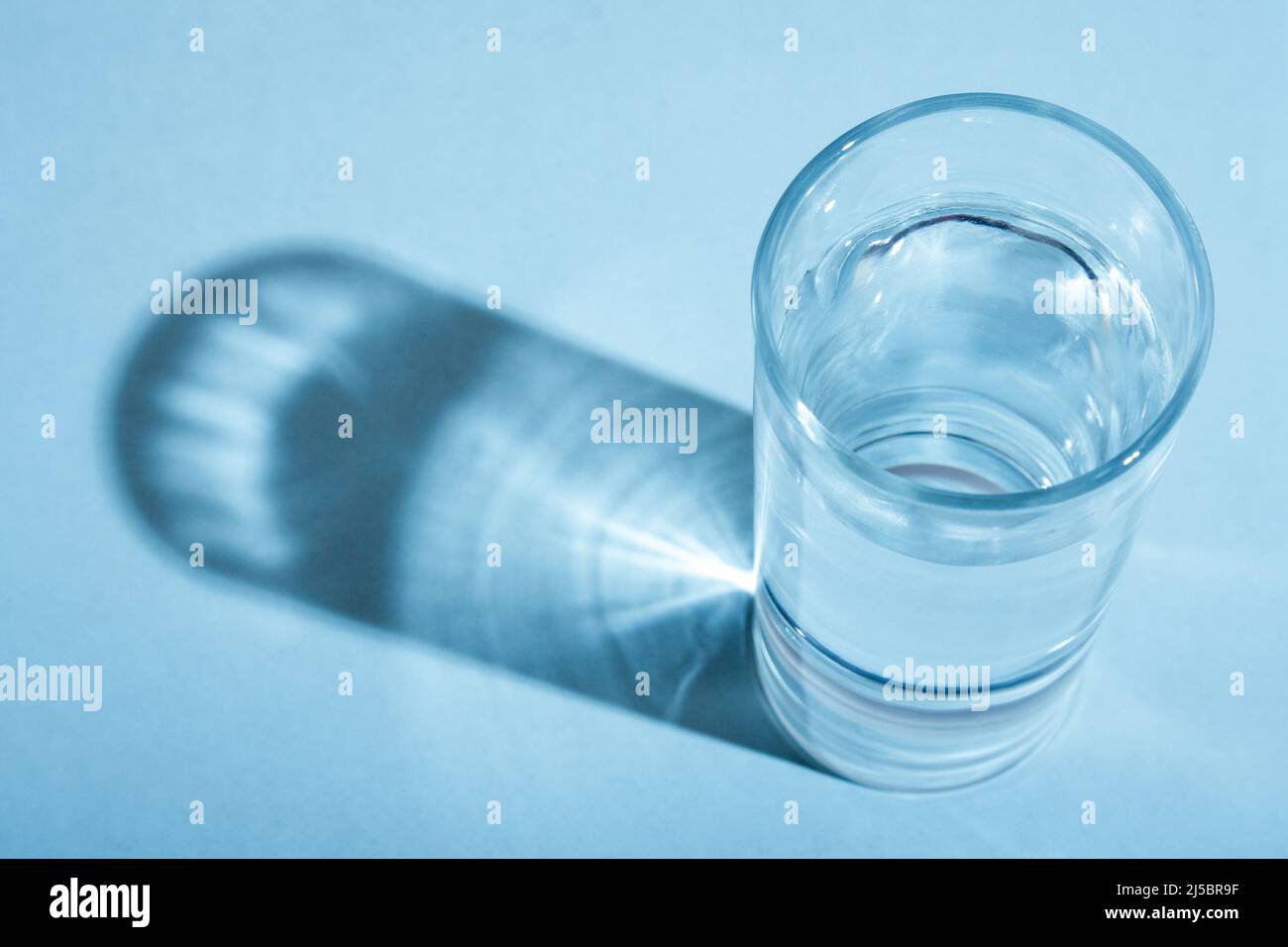 Glass of clean water with shadow in blue monochrome Stock Photo - Alamy
