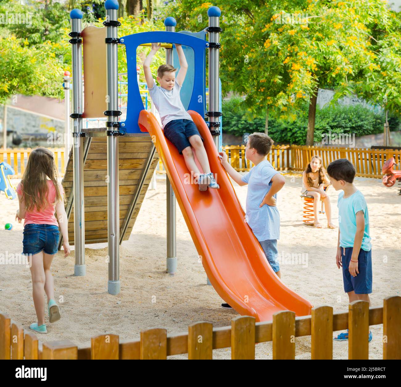 Kids playing on the slide at playground Stock Photo - Alamy