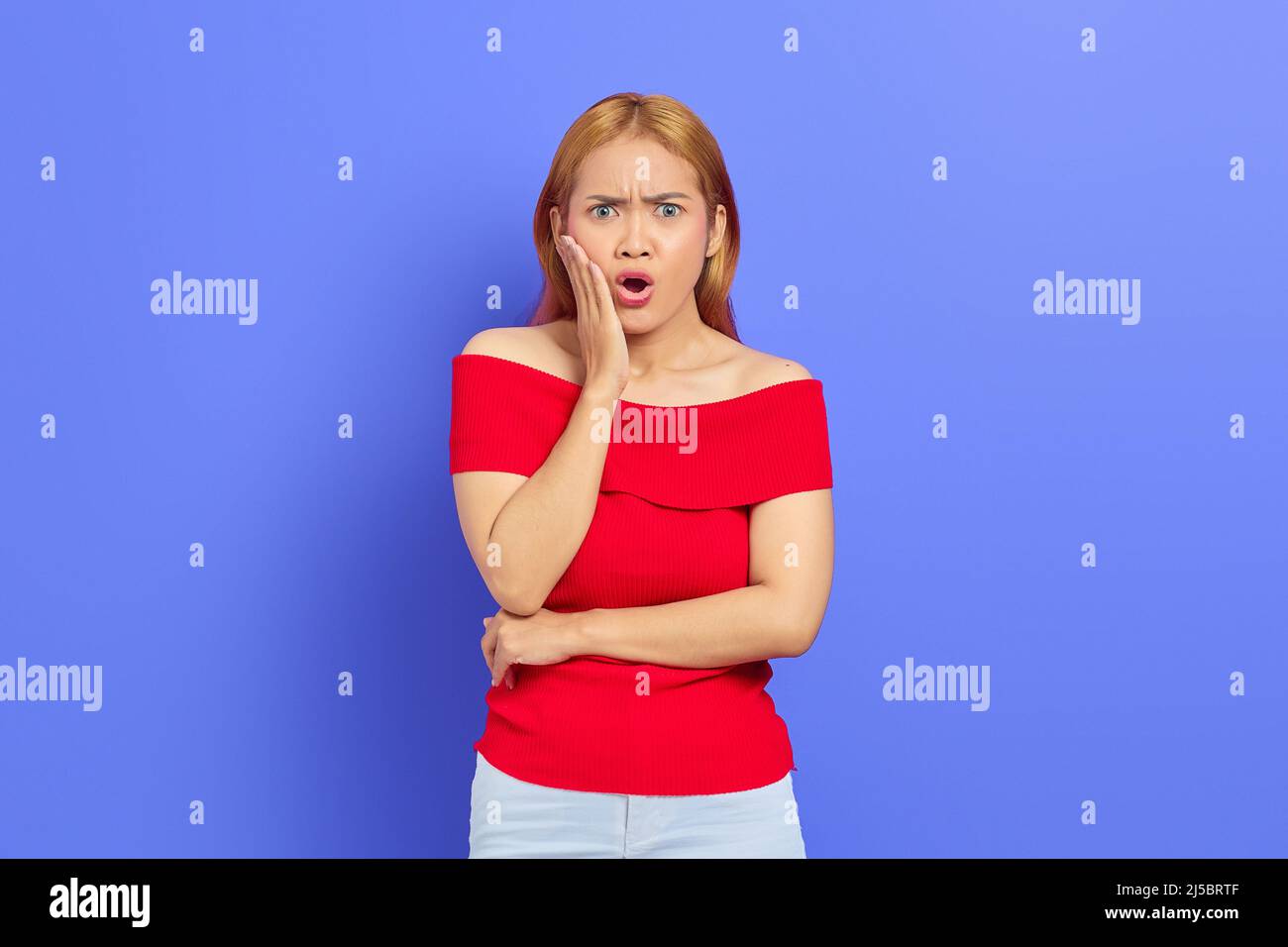 Amazed young Asian woman with open mouth looking forward and holding ...