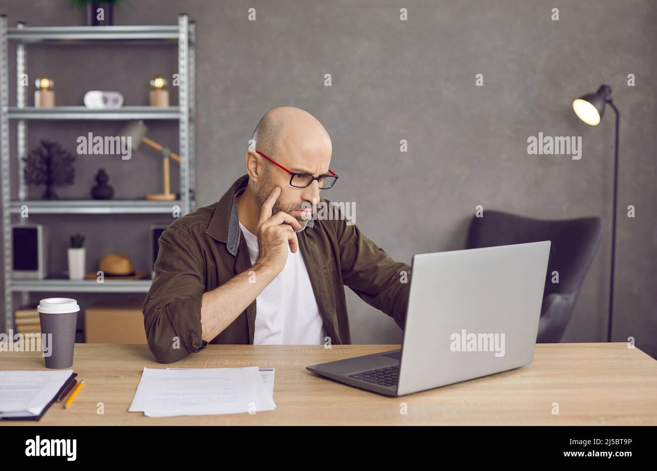 Focused businessman looking at laptop screen while reading important ...